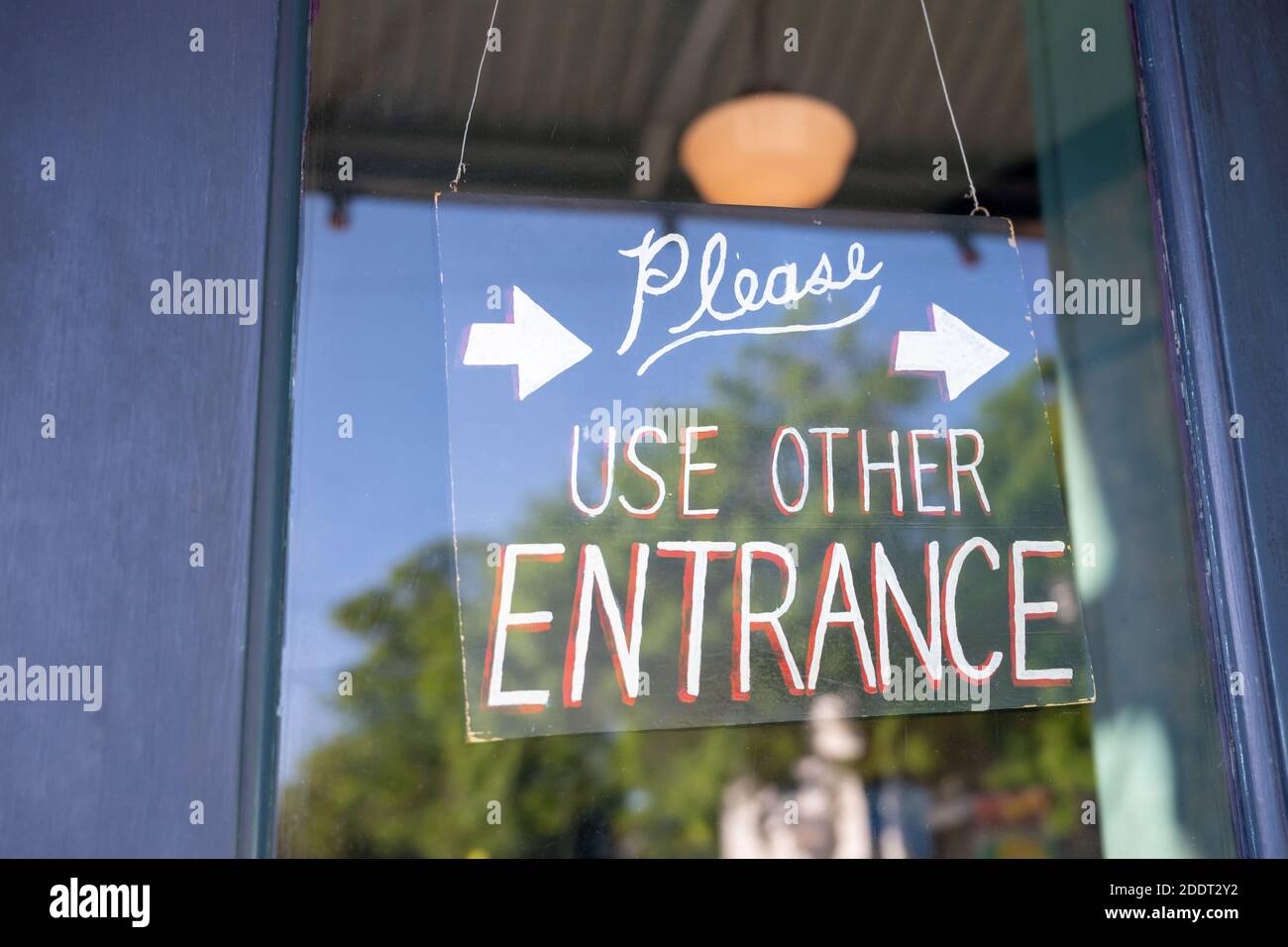 Please Use Front Entrance Sign Hanging Behind Glass Stock Photo - Alamy