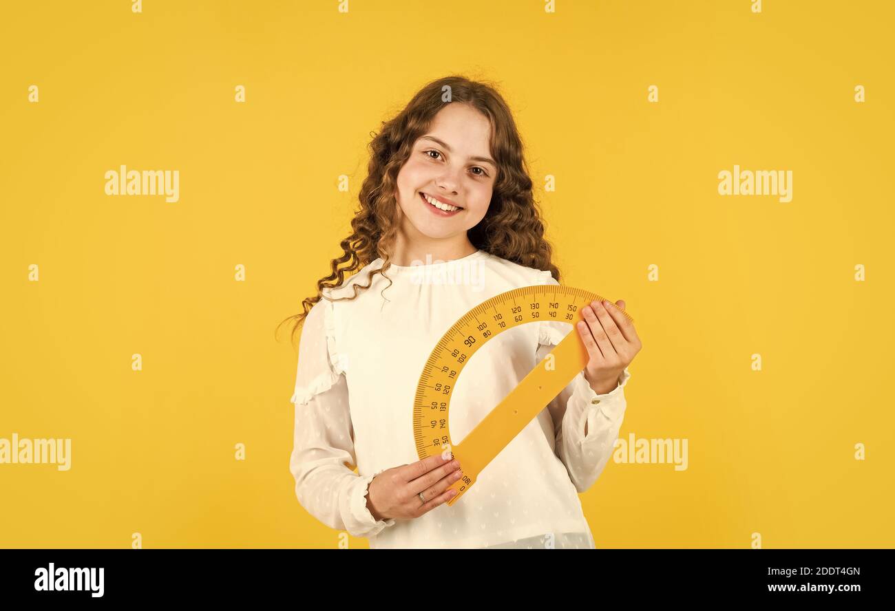 She loves studying. Small girl holding protractor for geometry lesson ...