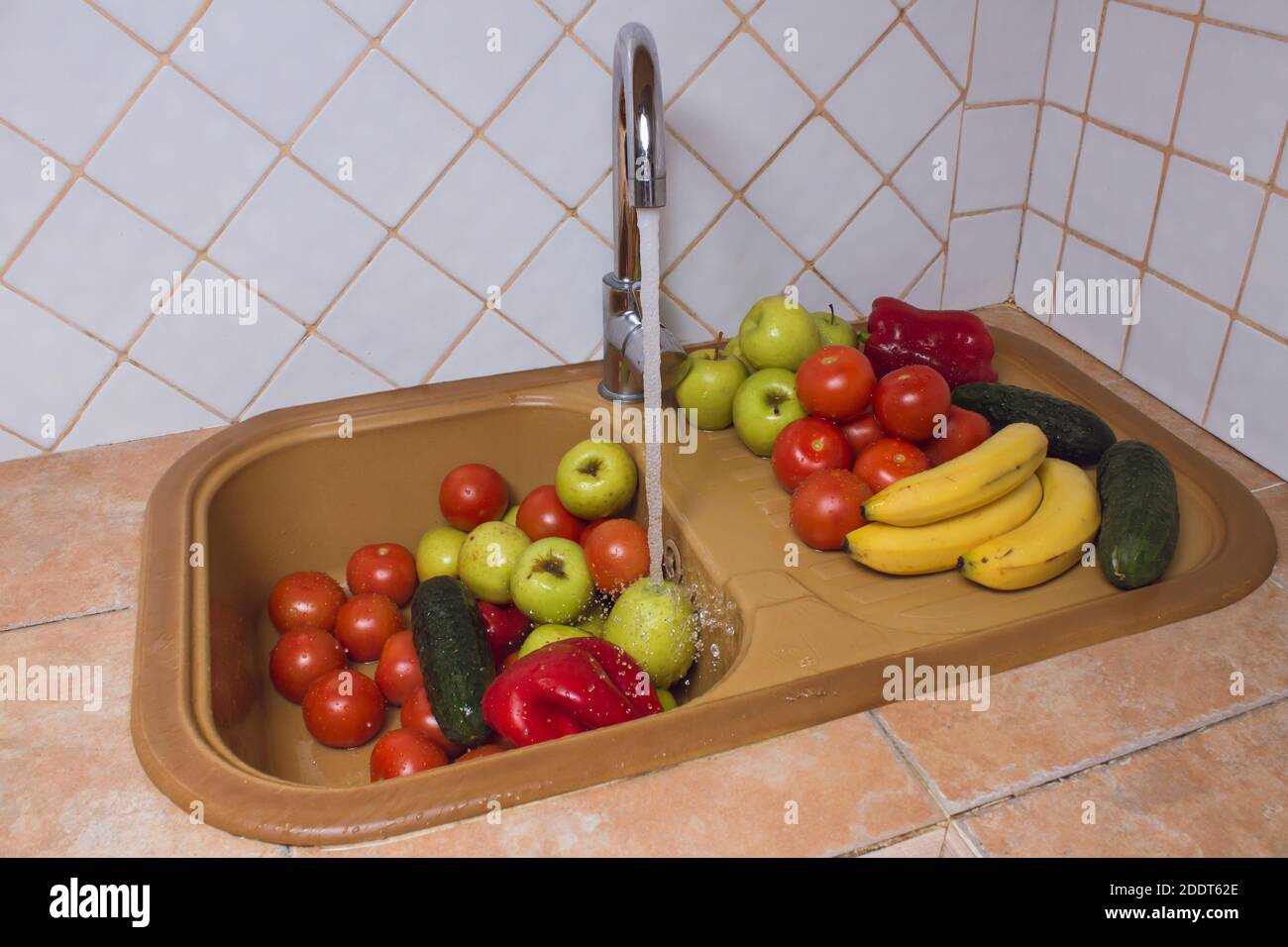 The jet of water washes fruits and vegetables in the sink of the rustic ...