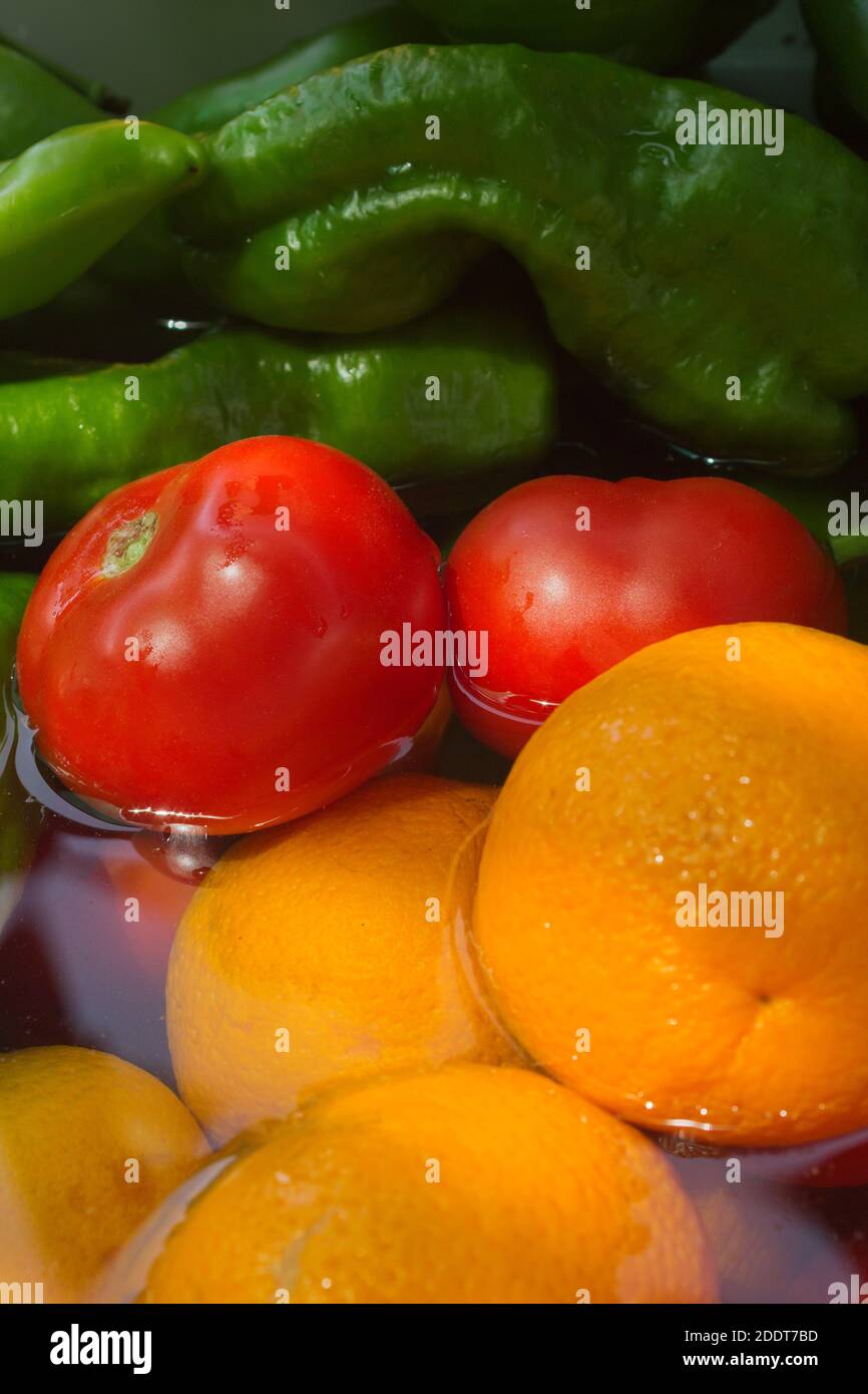Two tomatoes float between oranges and green peppers. A colorful ...