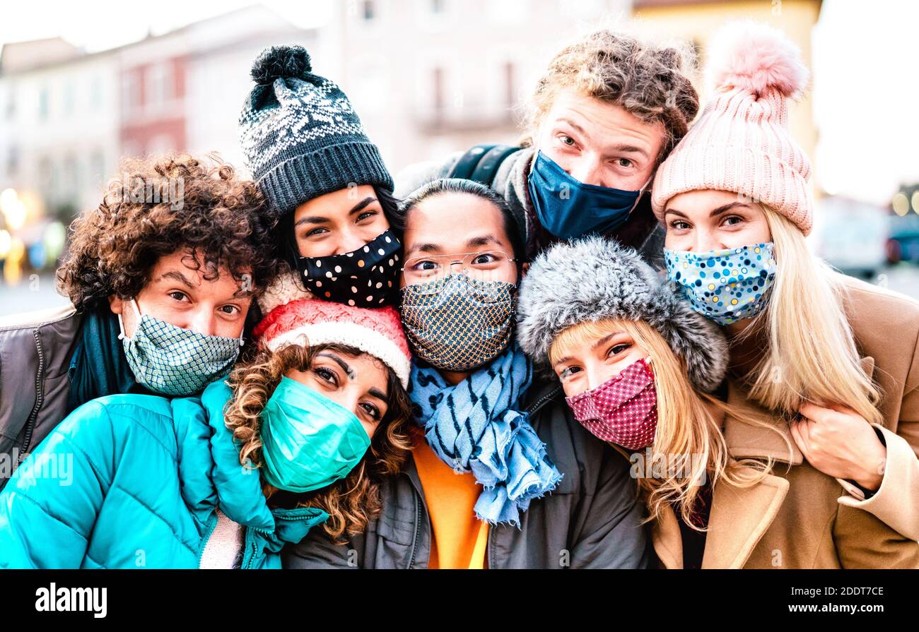 Multiracial friends taking selfie wearing face mask and winter clothes ...