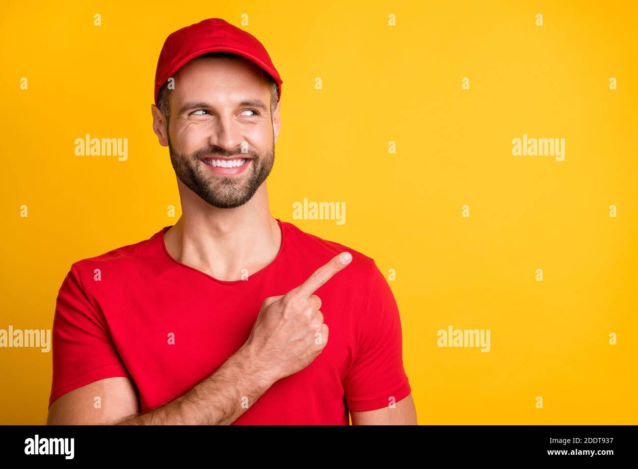 Photo of curious guy indicate finger look empty space wear red t-shirt hat isolated yellow color ...