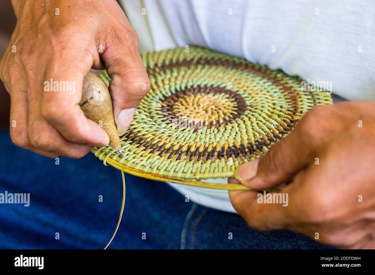 A pinikas artisan working on a basket using local materials at the ...