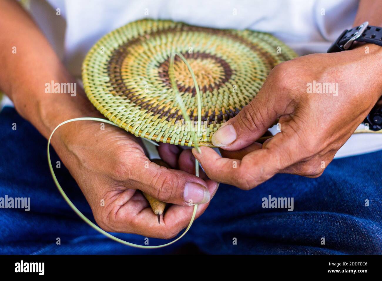 A pinikas artisan working on a basket using local materials at the ...