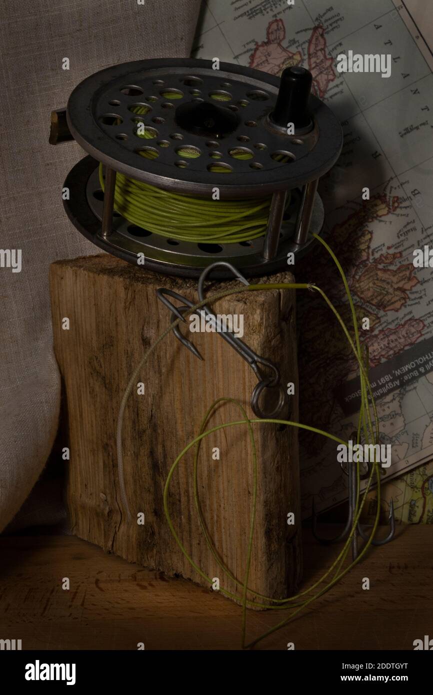 Fishing reel on top of wooden block with hook and line Stock Photo - Alamy