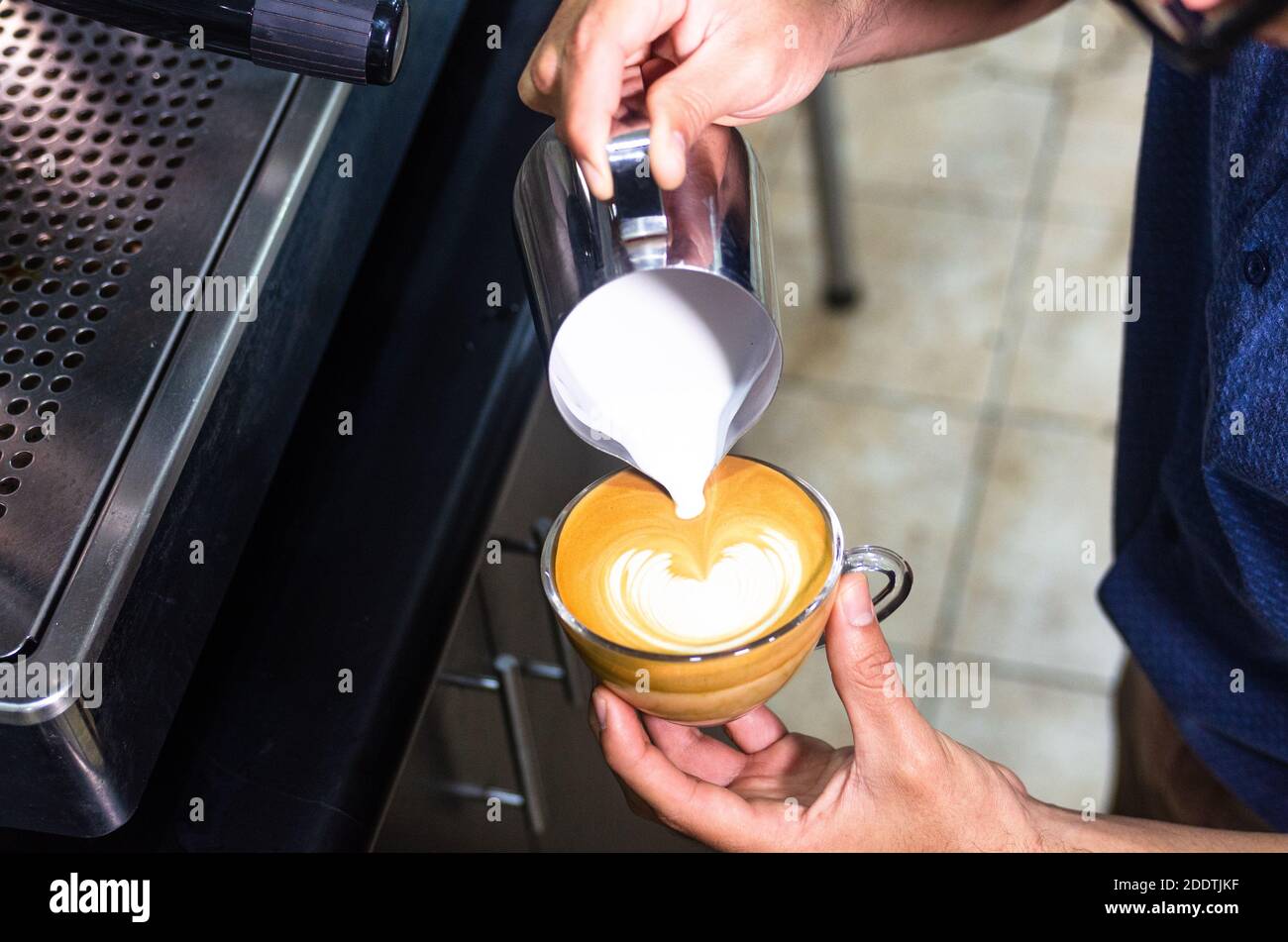 Hand of barista making latte or cappuccino coffee, pouring milk making ...