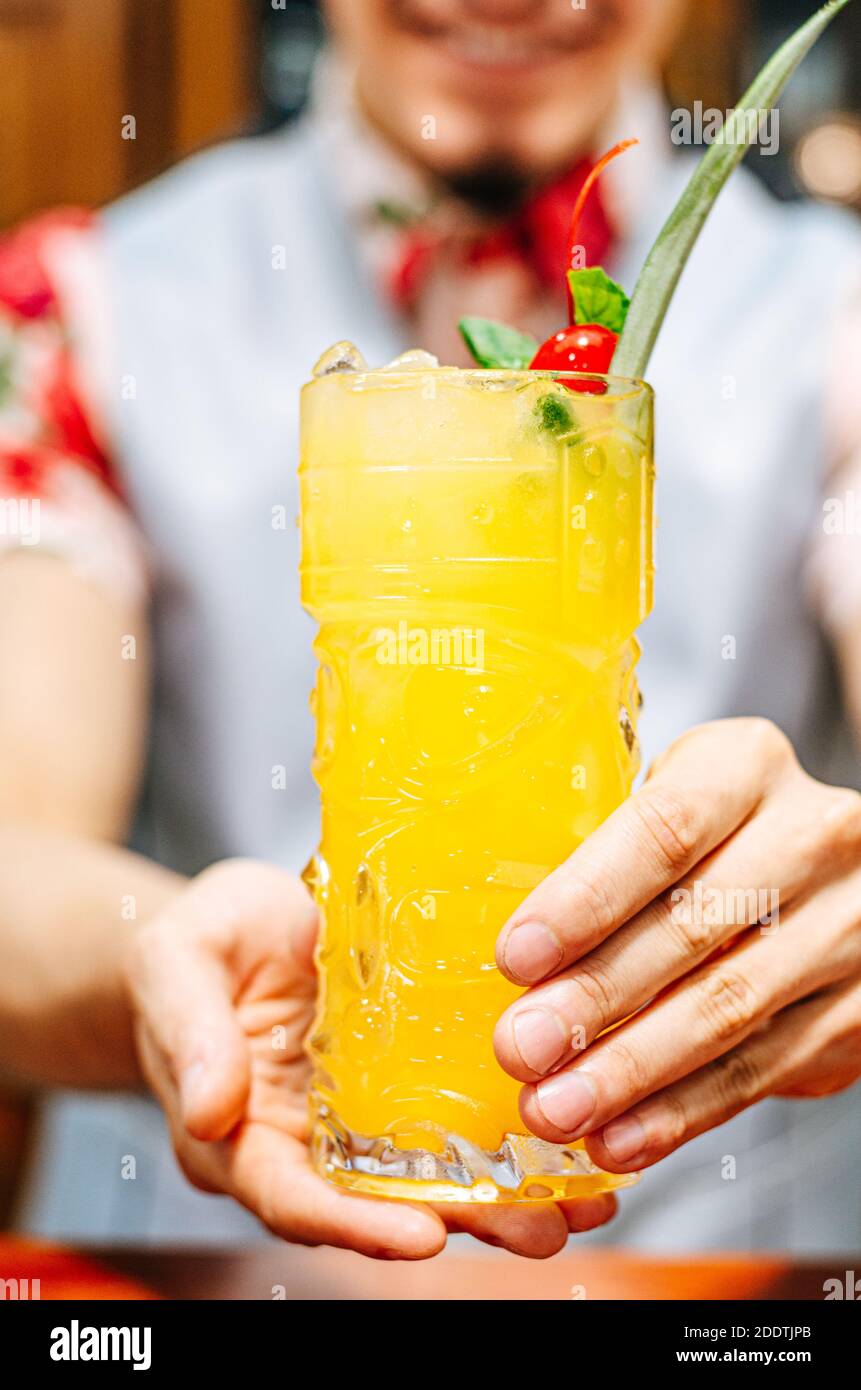 Bartender showing cocktail in a tiki glass on a bar counter on a ...