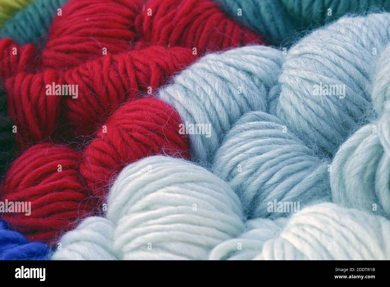 A pile of natural knitting yarn of red, blue and gray colors, is ready ...