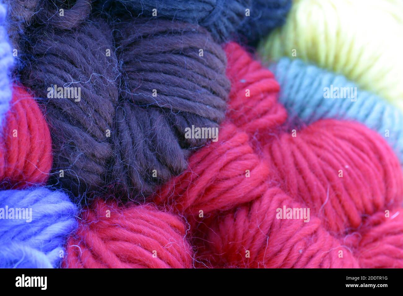 A pile of natural knitting yarn of red, blue and gray colors, is ready ...