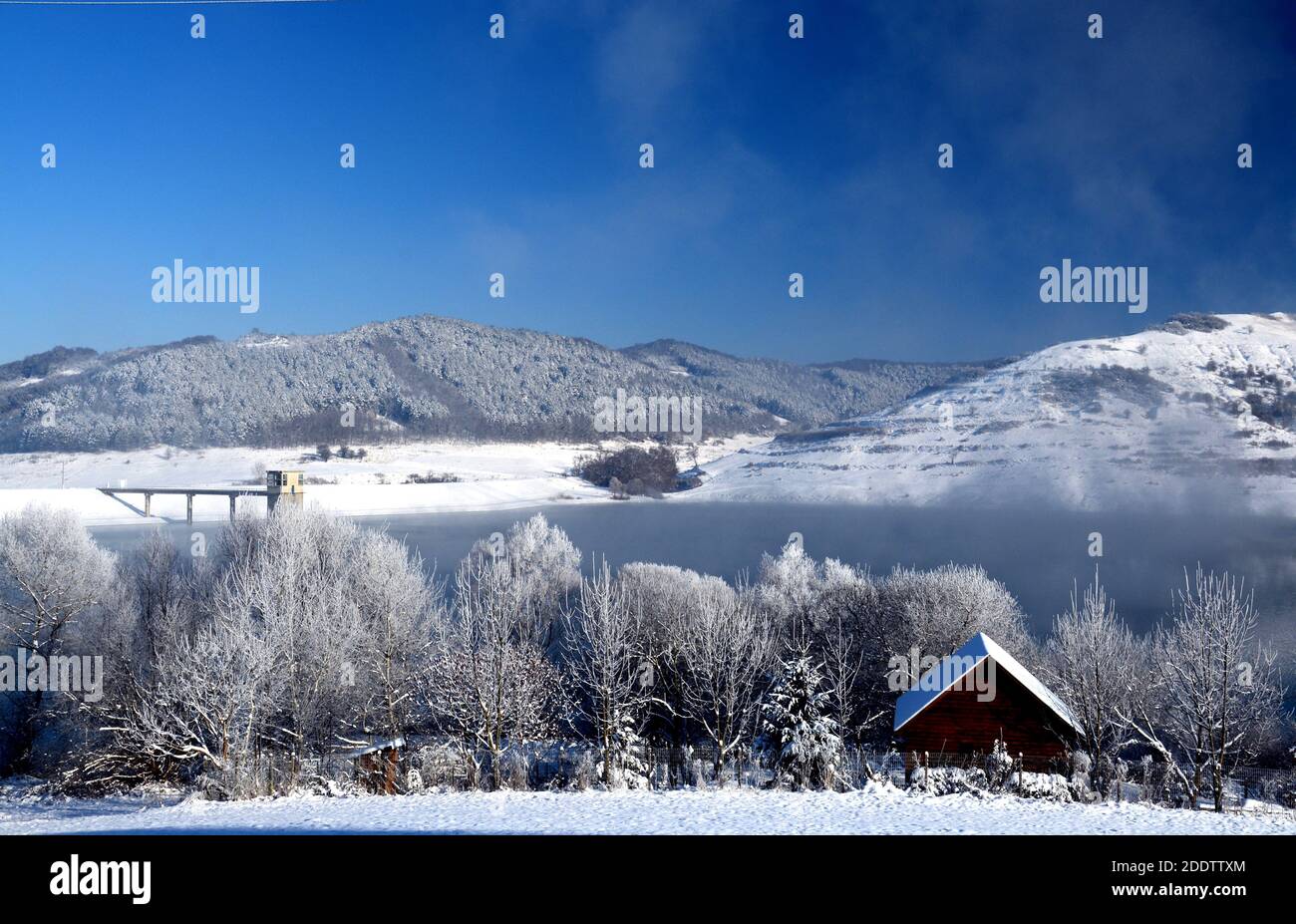 A beautiful winter scene of a lake, snow-covered trees, and hills Stock ...
