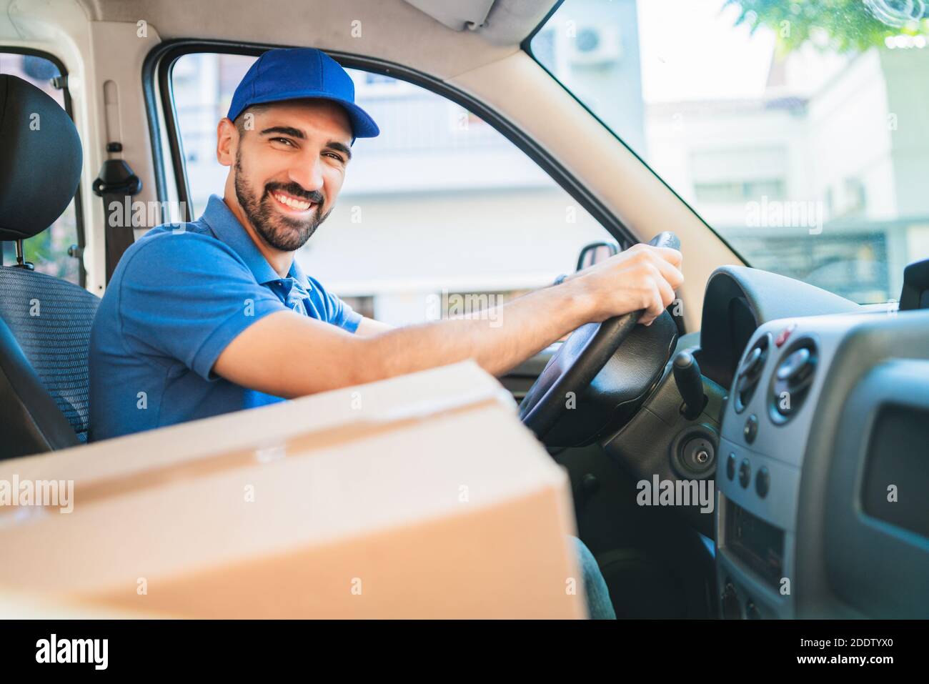 Delivery man driving van with cardboard boxes on seat Stock Photo - Alamy