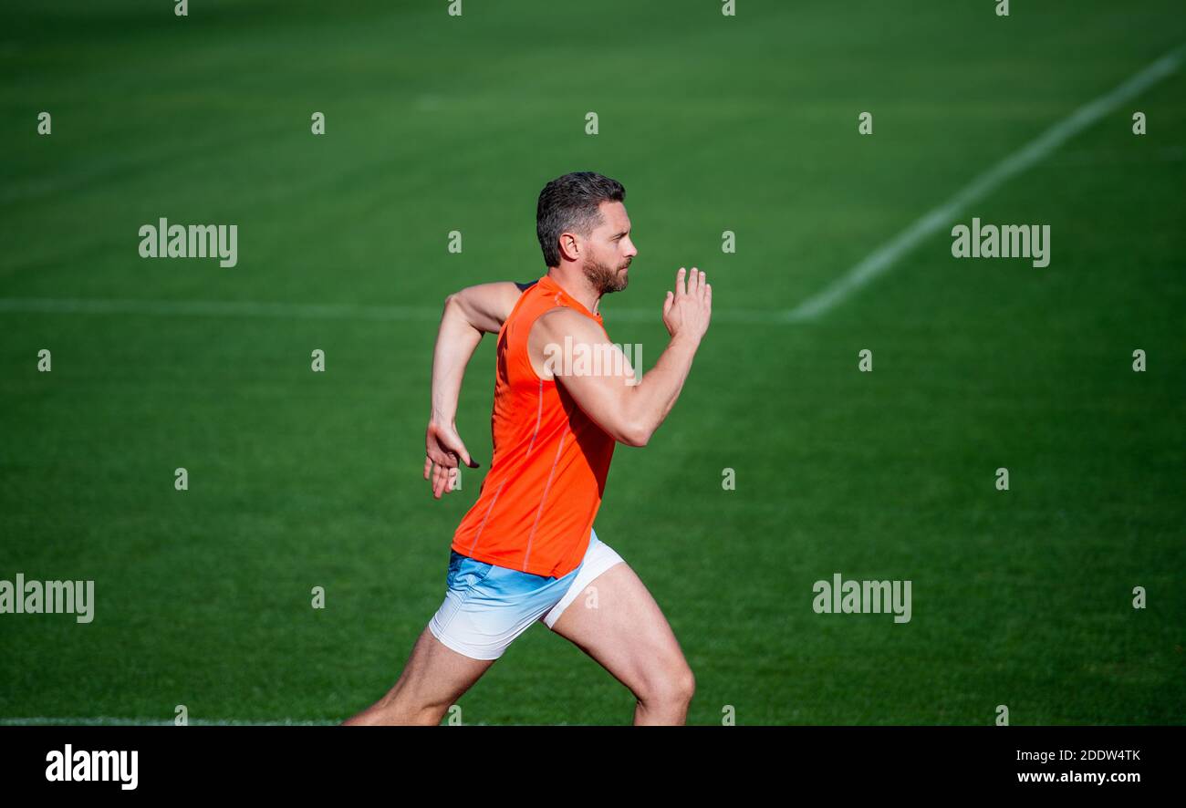 athletic muscular man running on racetrack at outdoor stadium, success ...
