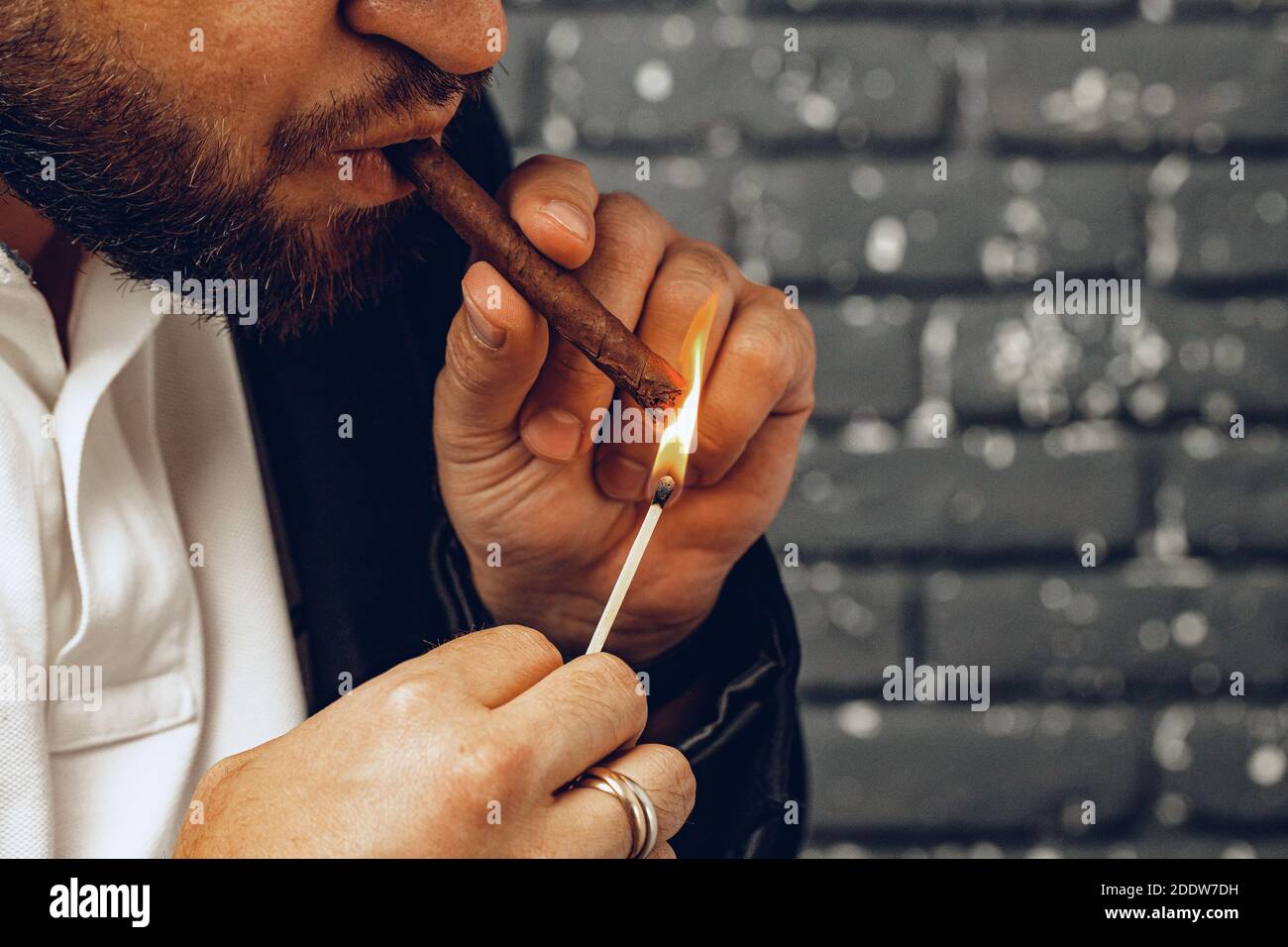 Bearded man smoking cigar against black brick wall Stock Photo - Alamy