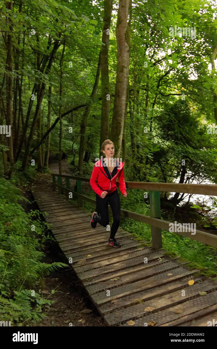Woman running over boarded footpath during a trail running session in ...