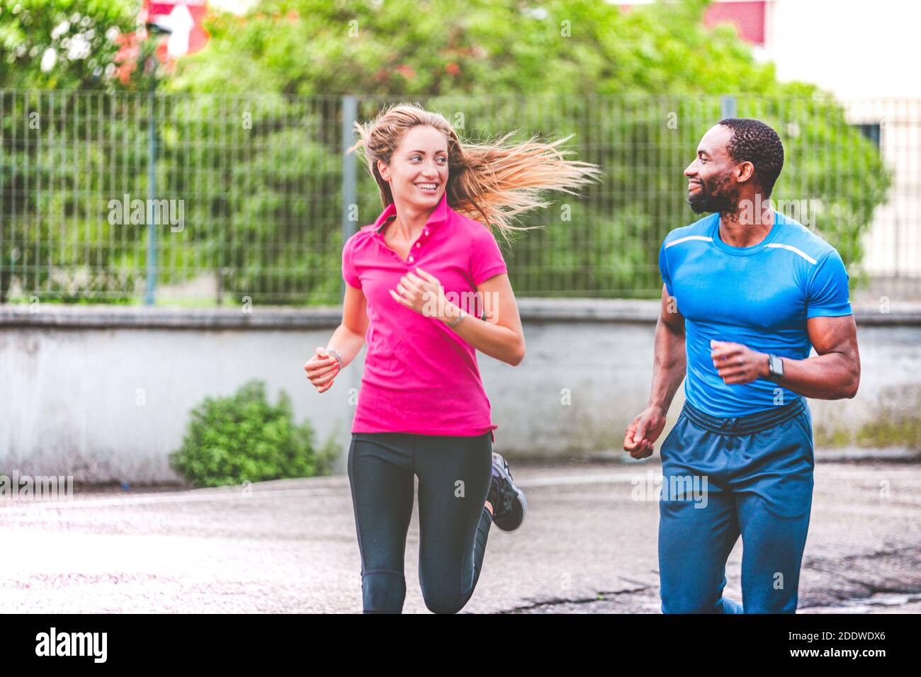 Young couple smiling to each other while jogging on the street, out to ...