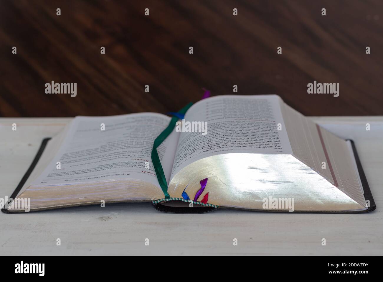 Open bible on white bible stand, viewed from side, dark background with ...