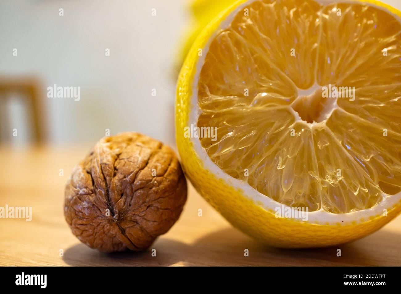 A close up shot of a cut lemon and a walnut on a wooden table Stock ...