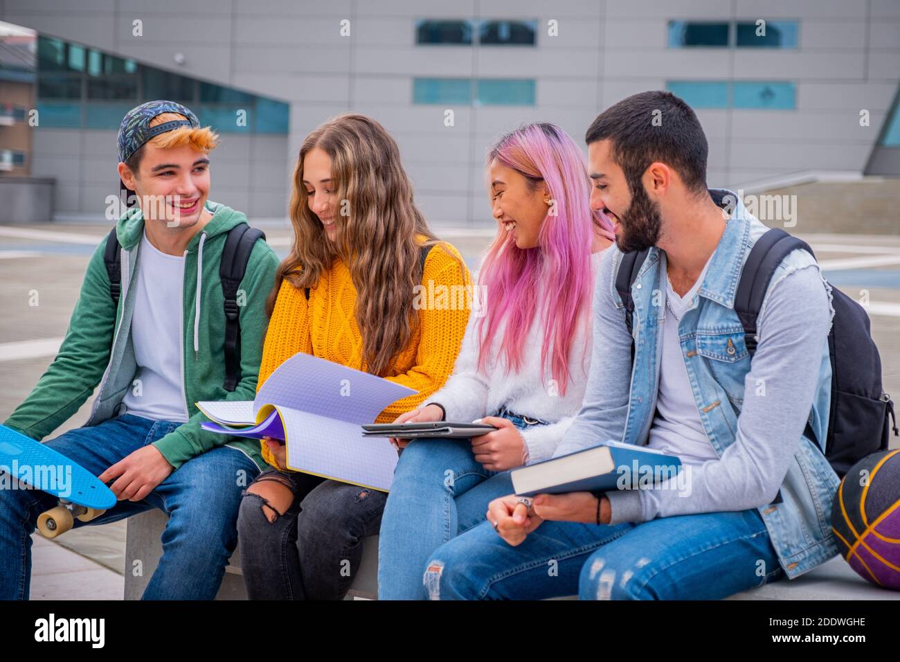 Multiethnic Students Joking And Talking Sitting On The Bench Together