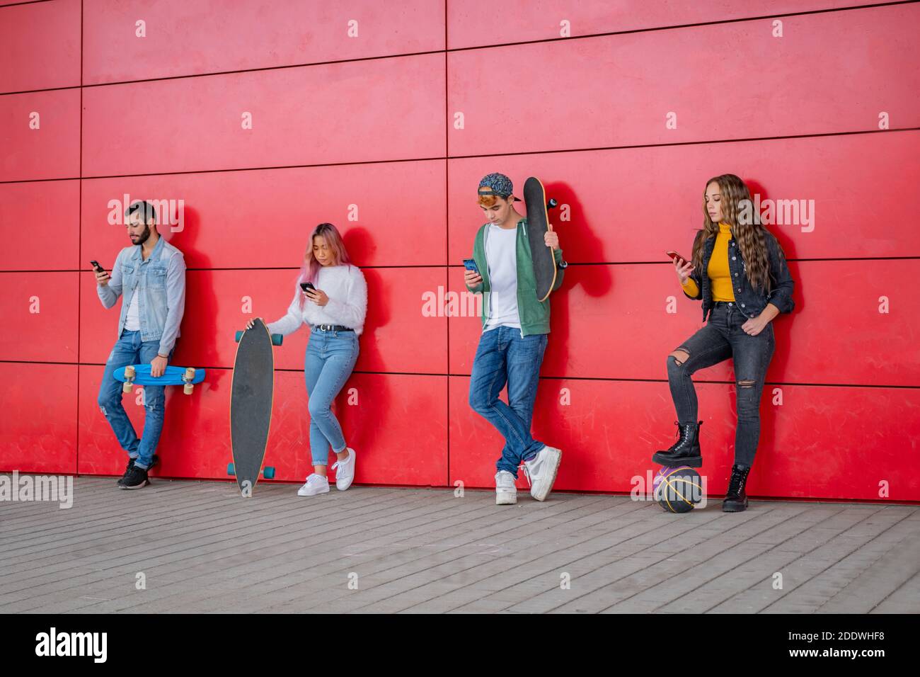 Group of young friends stare at their cell phones while standing ...