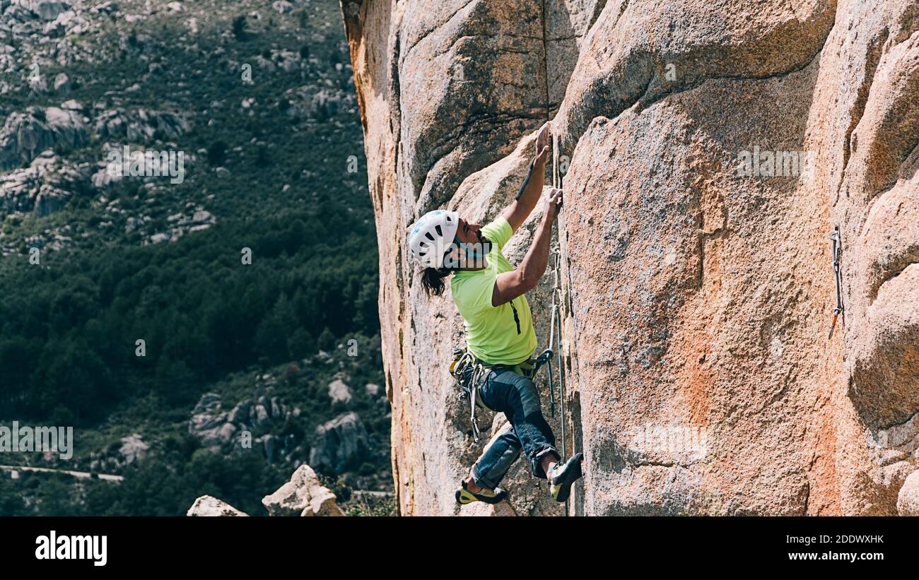 Top view of strong man looking up while climbing rocks. He is wearing a ...