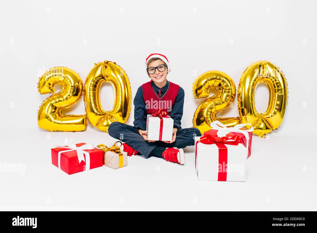 Happy little boy in Santa hat, stylish baby with Christmas gifts, sits ...