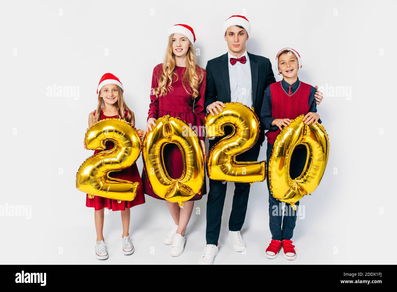 Young happy family with kids wearing Santa hats holding balloons shaped ...