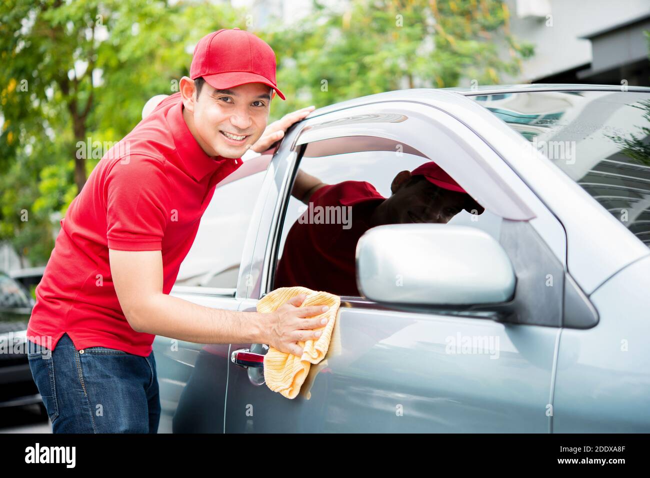Worker in red uniform cleaning car - auto detailing and valeting ...
