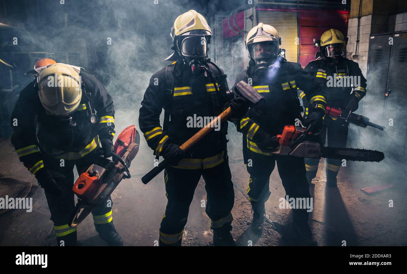 Group of firefighters with chainsaw and sledge hammer practicing in the ...