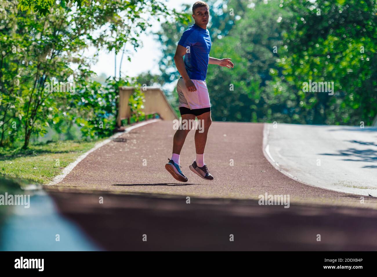 Athletic young man running on the race track in a sports park Stock ...