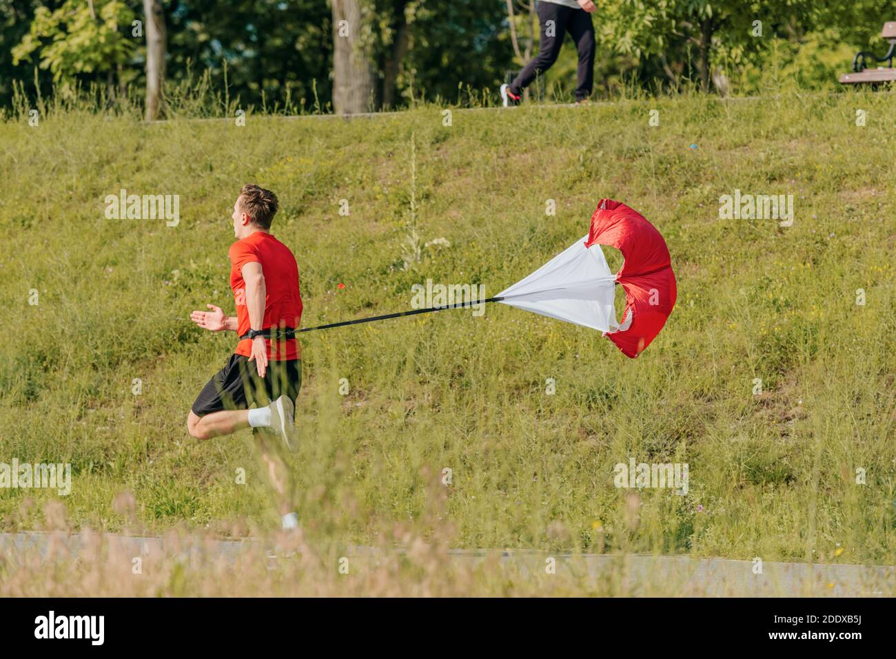 Side view of a strong man doing workout using resistance parachute ...