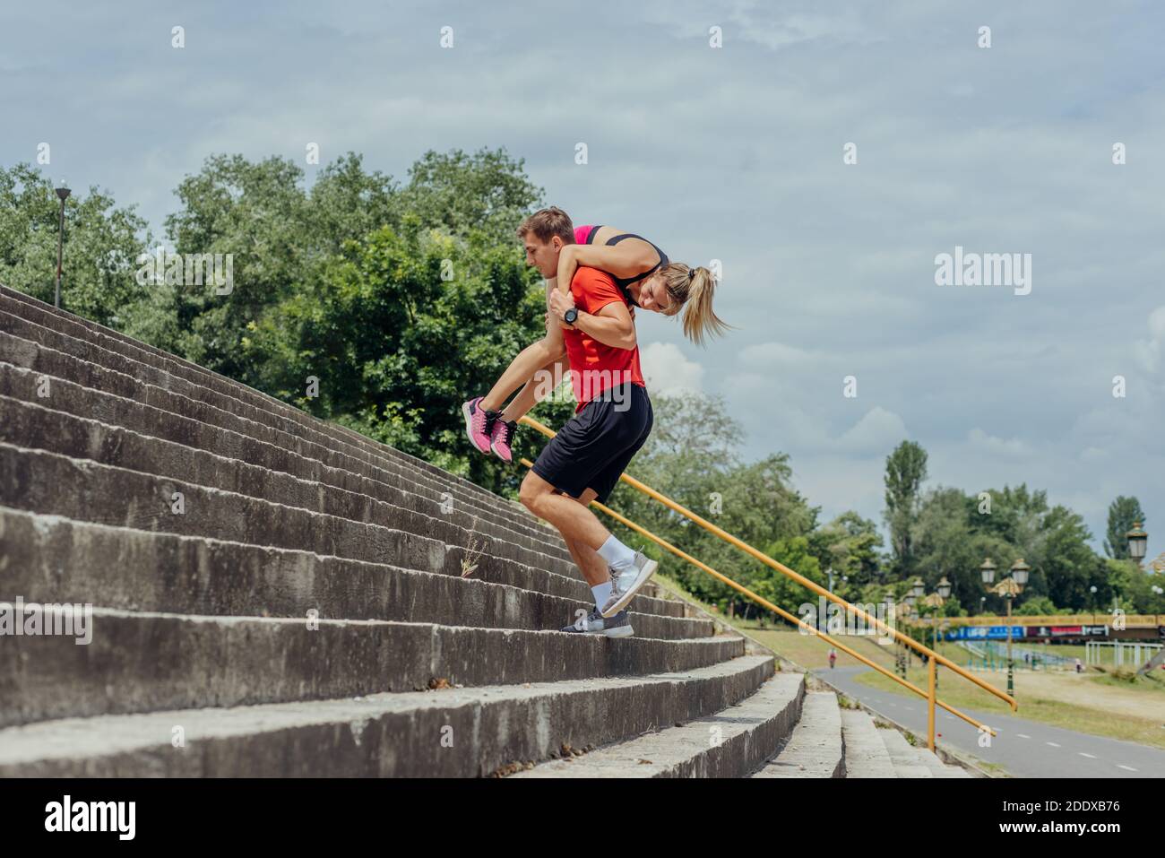 Male athlete carrying his female workout partner on his shoulders while ...