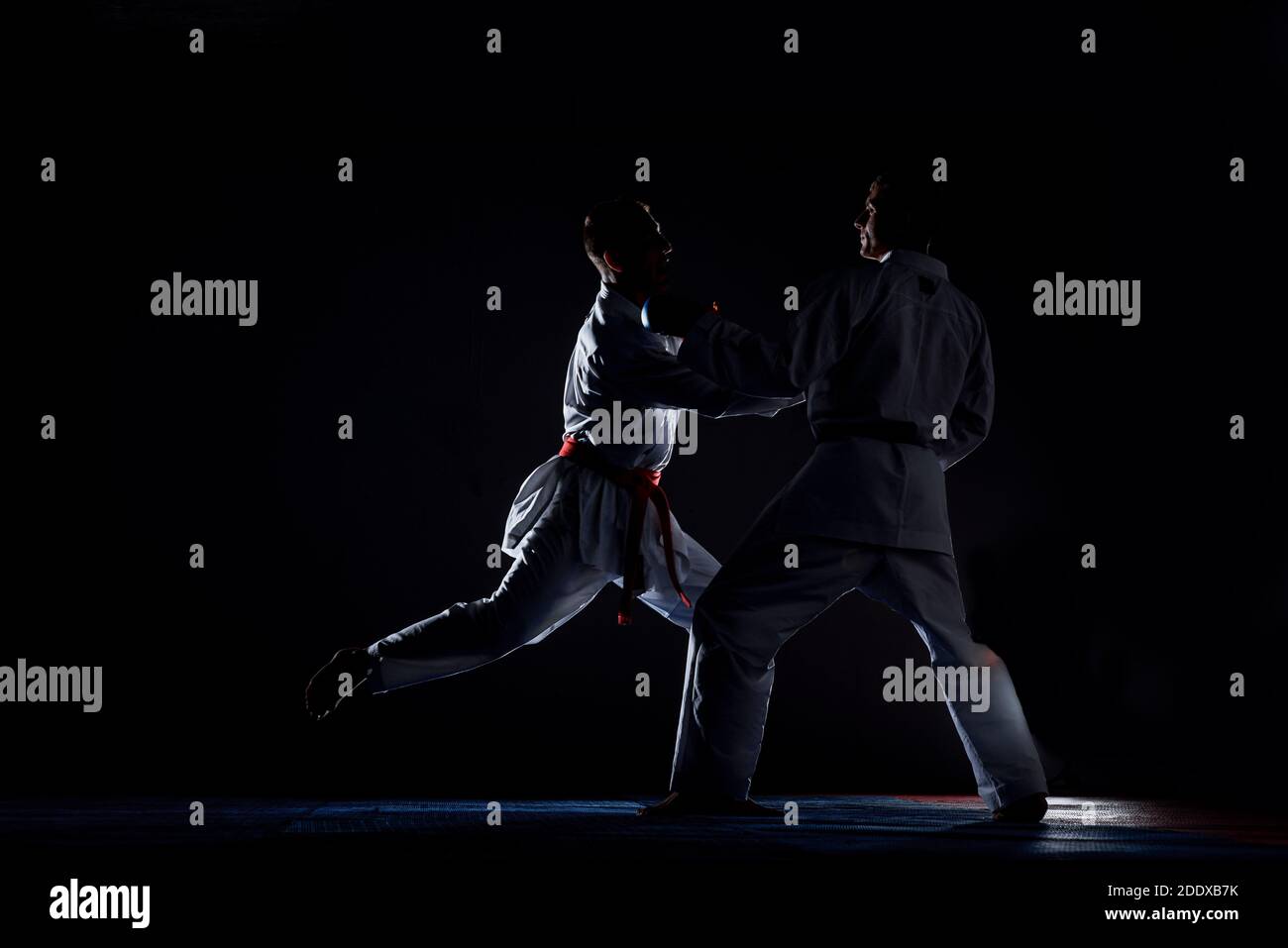 An athlete with a red belt and in karategi performs a formal karate ...