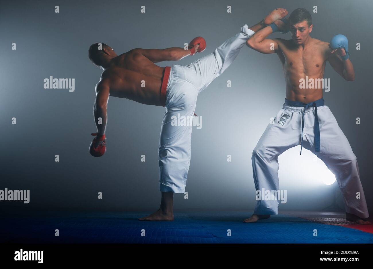 An athlete with a red belt and in karategi performs a formal karate ...