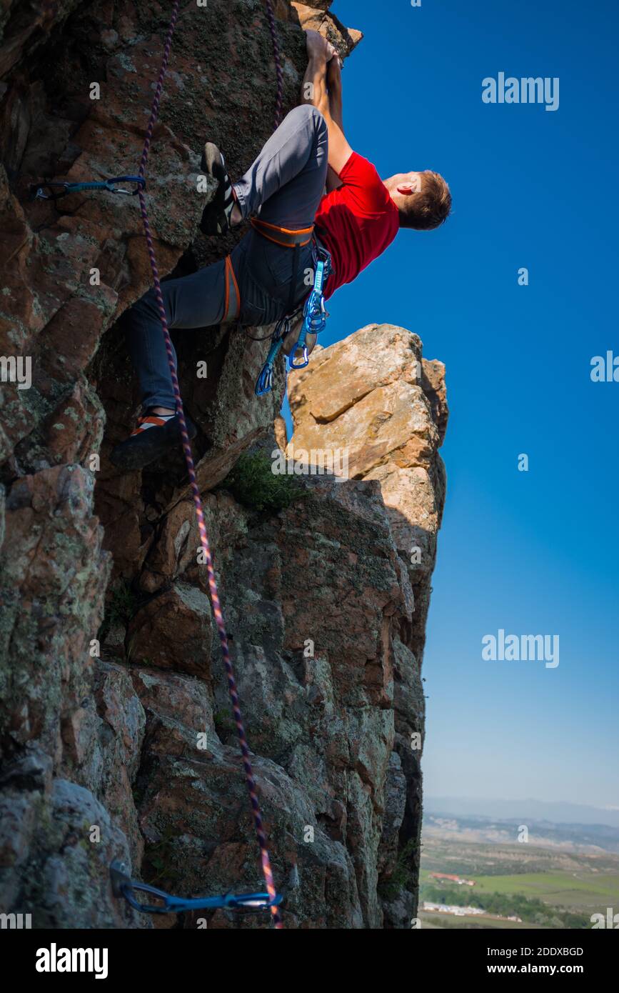 Man climbing a rock short before reaching the summit Stock Photo - Alamy