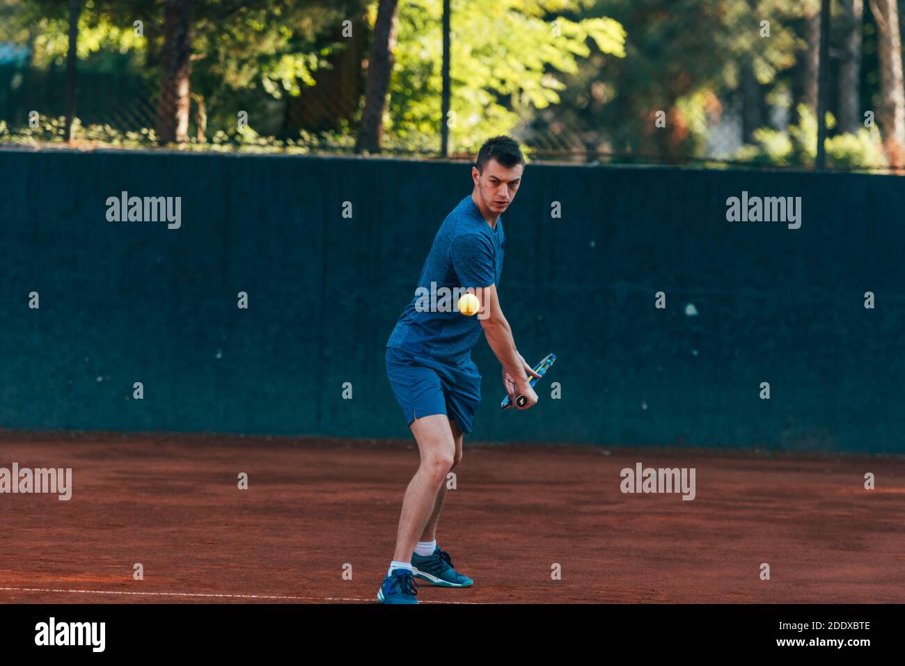 Professional equipped male tennis player beating hard the tennis ball ...