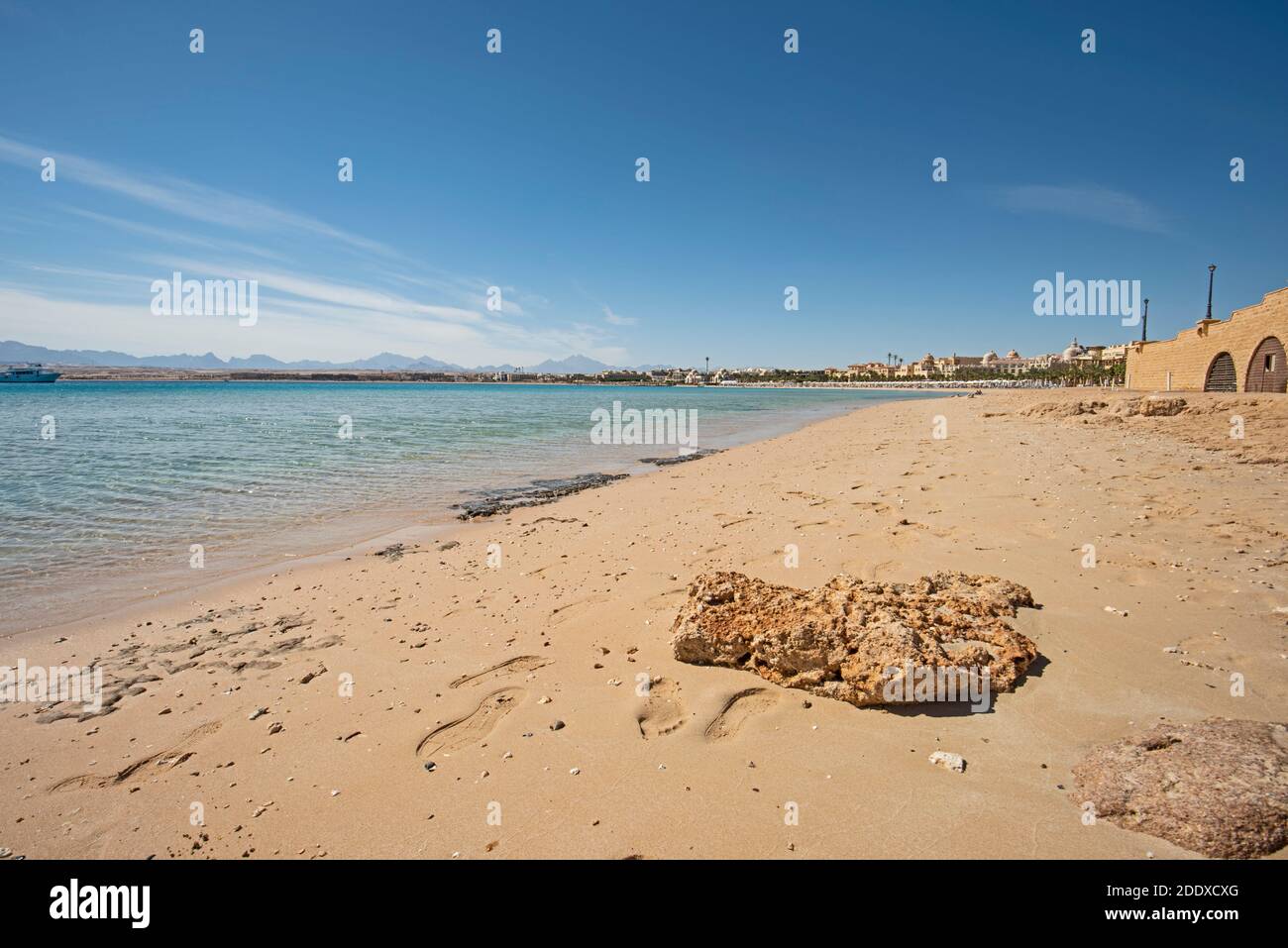 Closeup view across an empty sandy tropical beach shoreline in resort ...