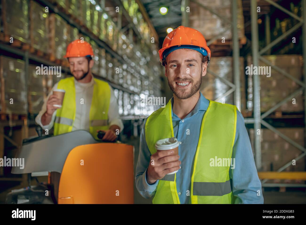 Warehouse workers in orange helmets having coffee break Stock Photo - Alamy