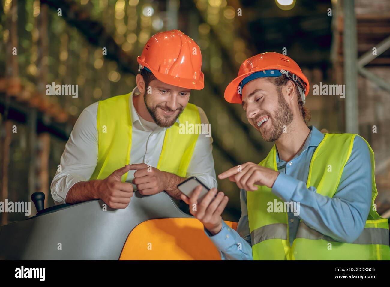 Warehouse worker showing something on his smartphone to the coworker ...