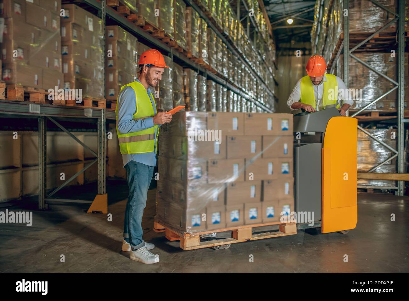 Male warehouse workers in helmets standing near containers Stock Photo ...
