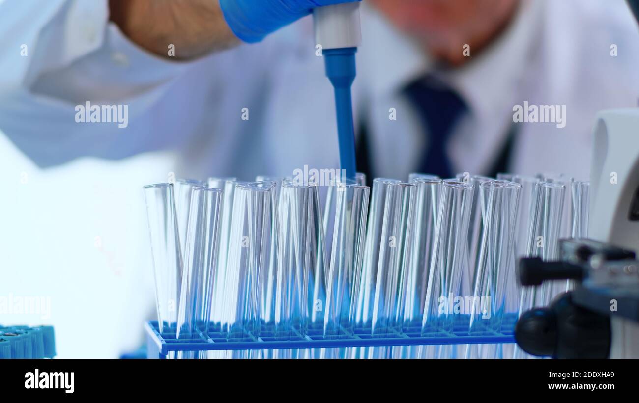 Close up of chemist filling test tube with liquid using pipette in ...