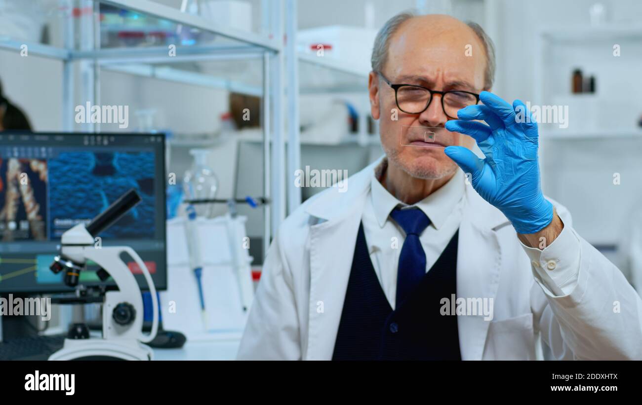 Mature man lab technician looking at virus sample in modern equipped ...