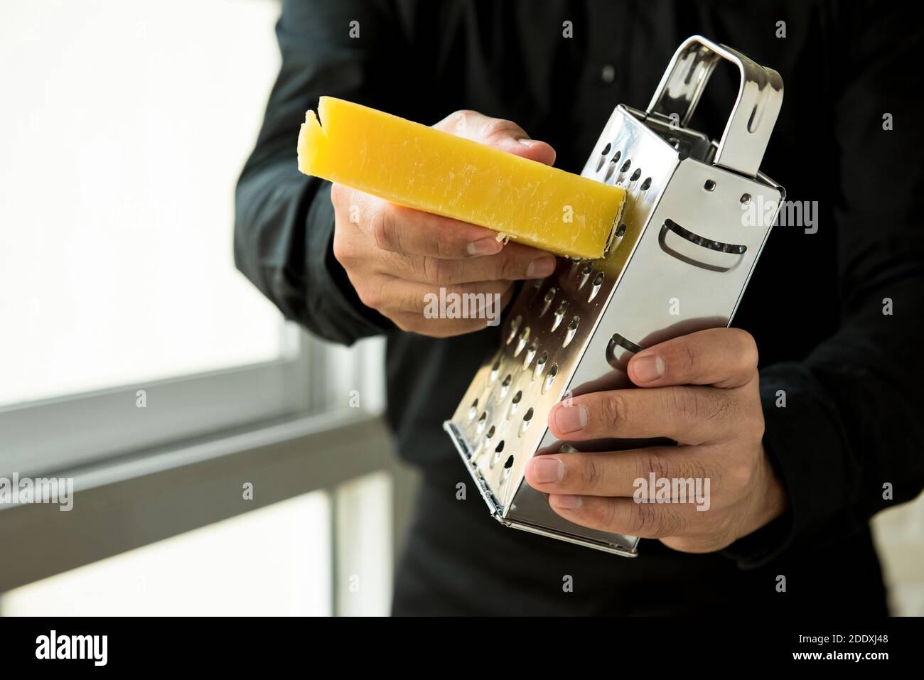 Chef grating Italian parmesan cheese with metal grater in the kitchen ...