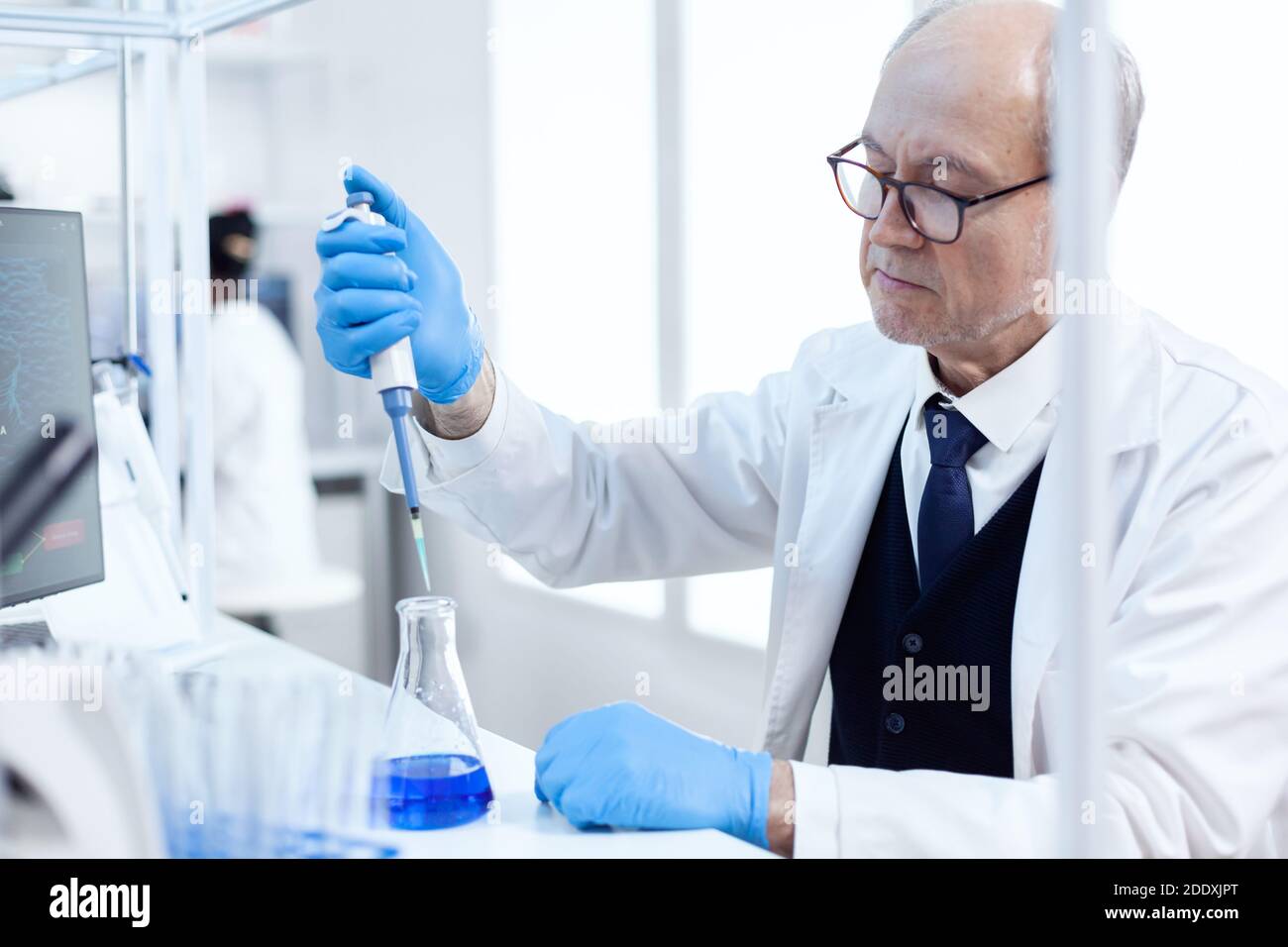 Elderly scientist doing genetic experiment in busy laboratory using ...