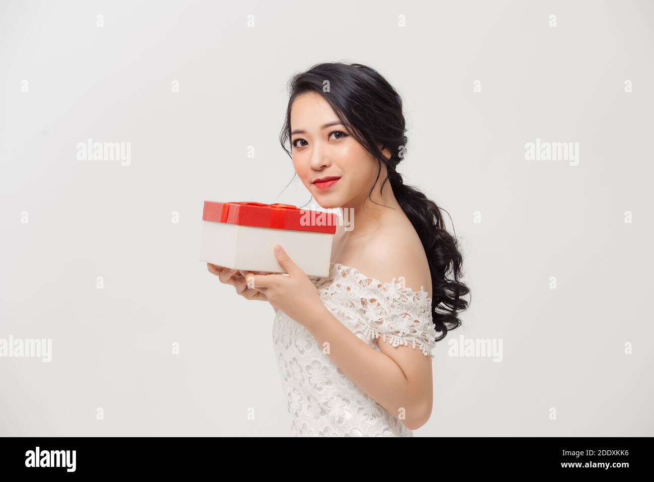 Happy beautiful young Asian woman holding gift box isolated over white ...