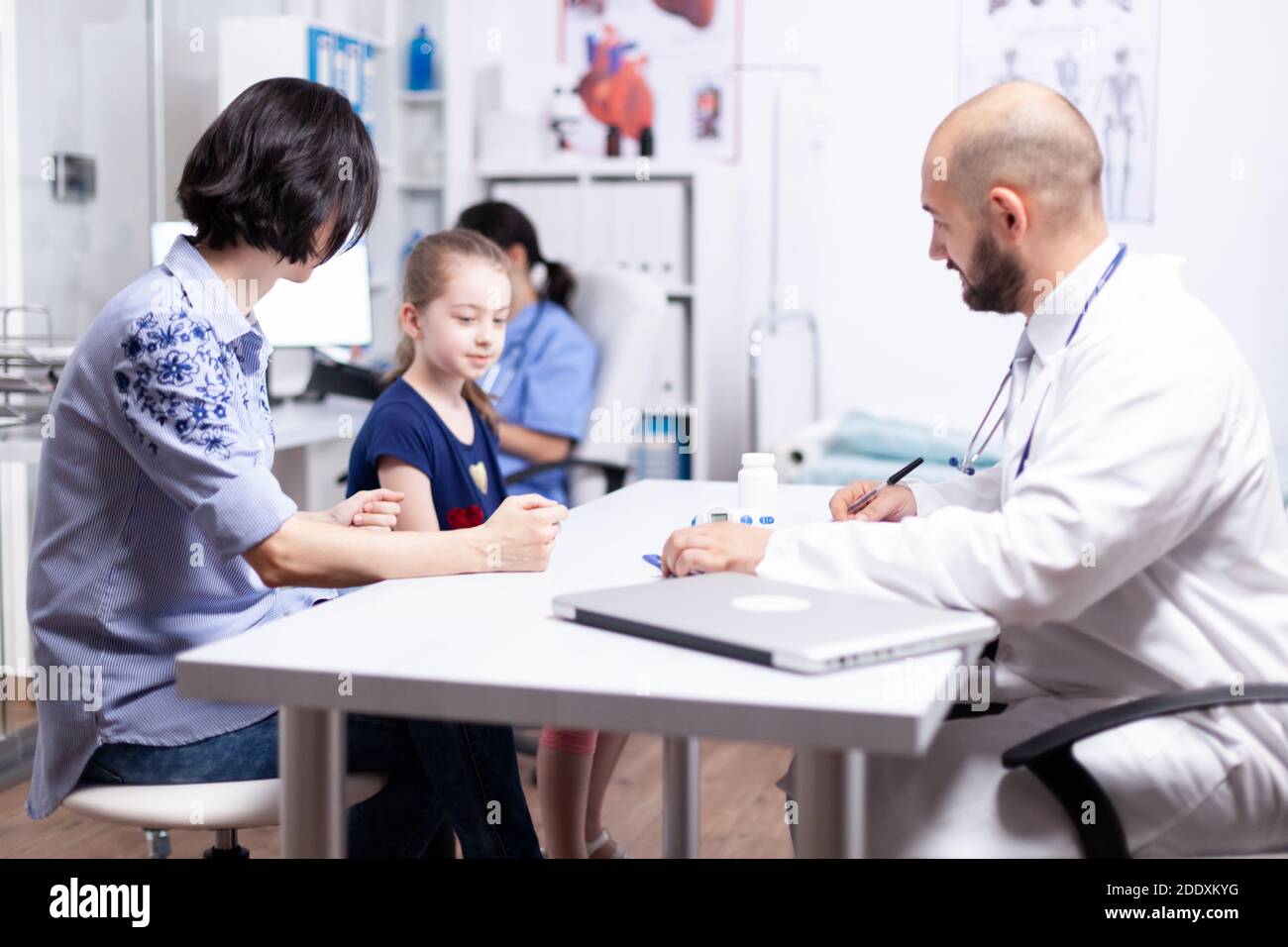 Pediatrician writing treatment after consultation of sick child in ...