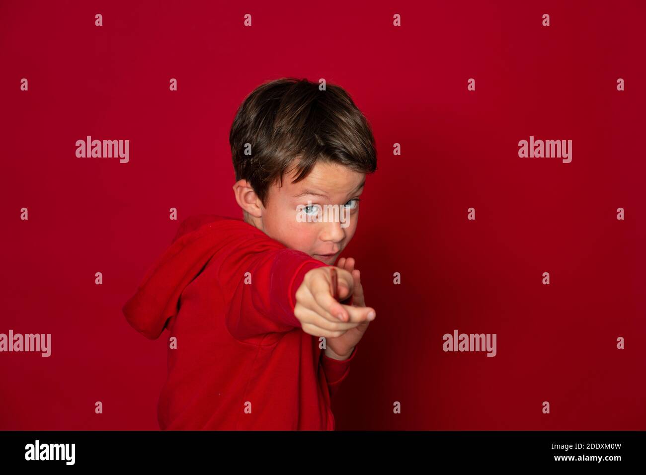 cool young school boy is posing with red pencil in ront of red ...