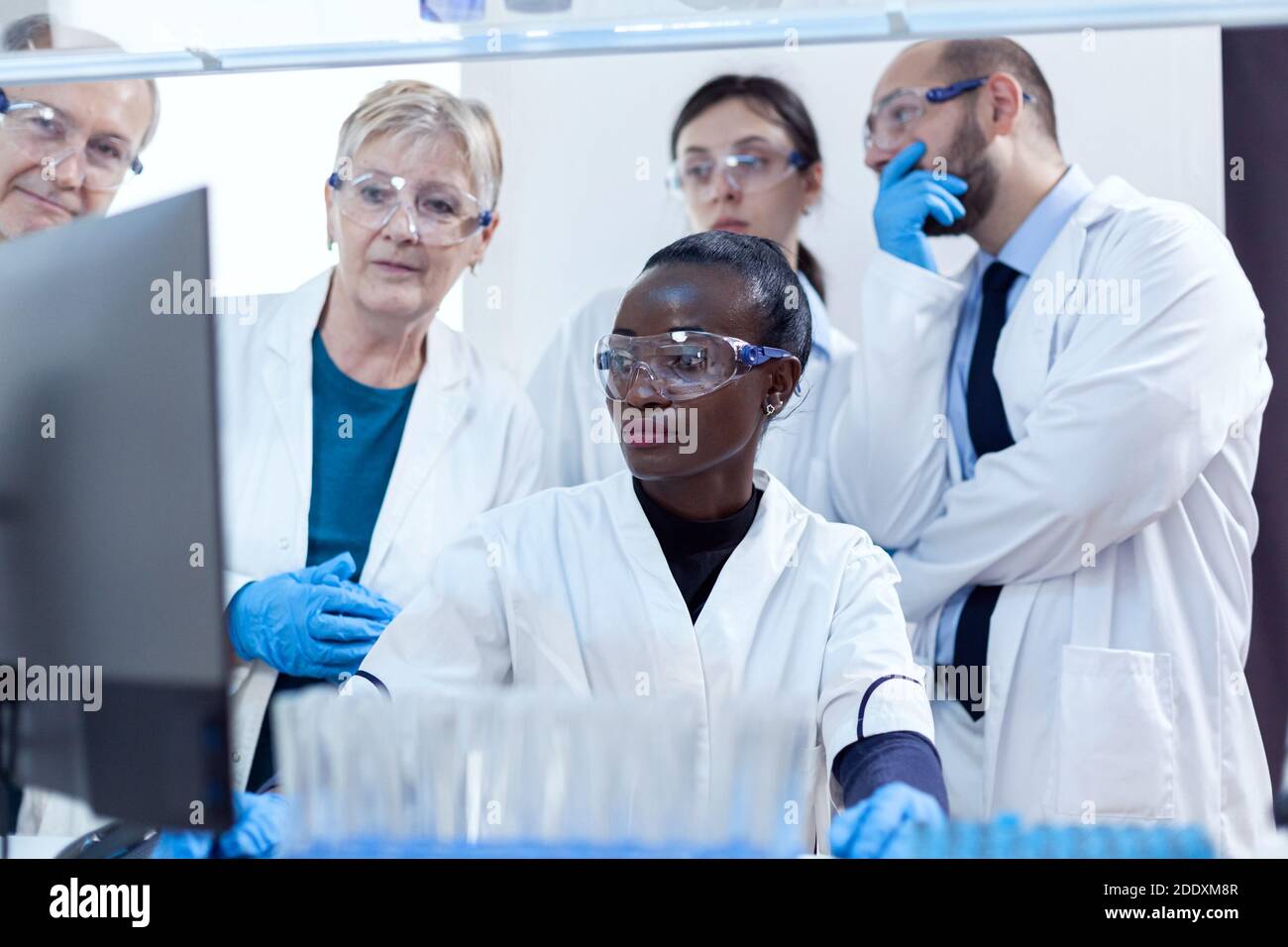 Group of scientists in medicine lab looking at computer display ...