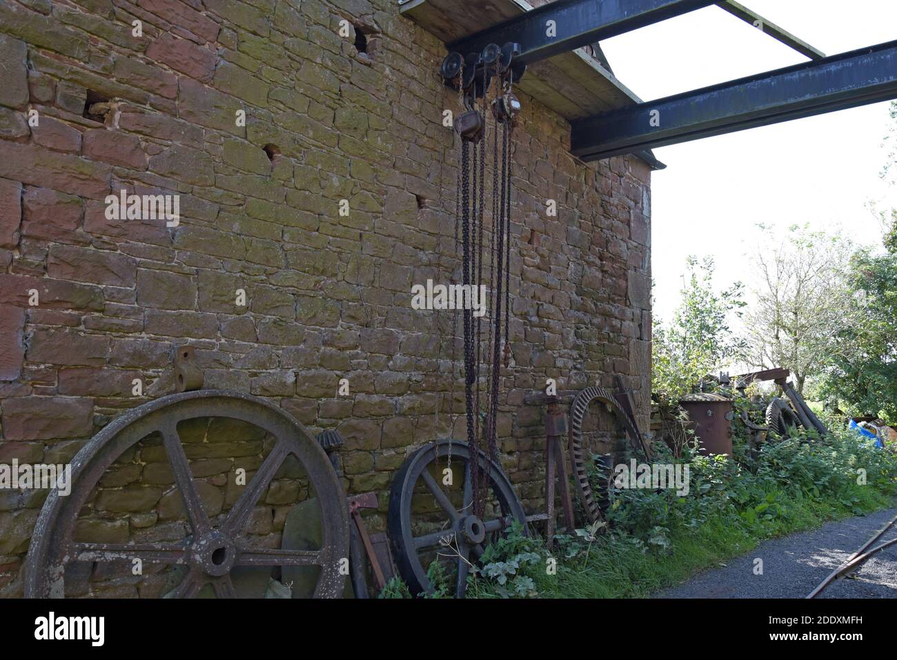 A pair of large chain hoists on a large steel beam hanging between 2 ...