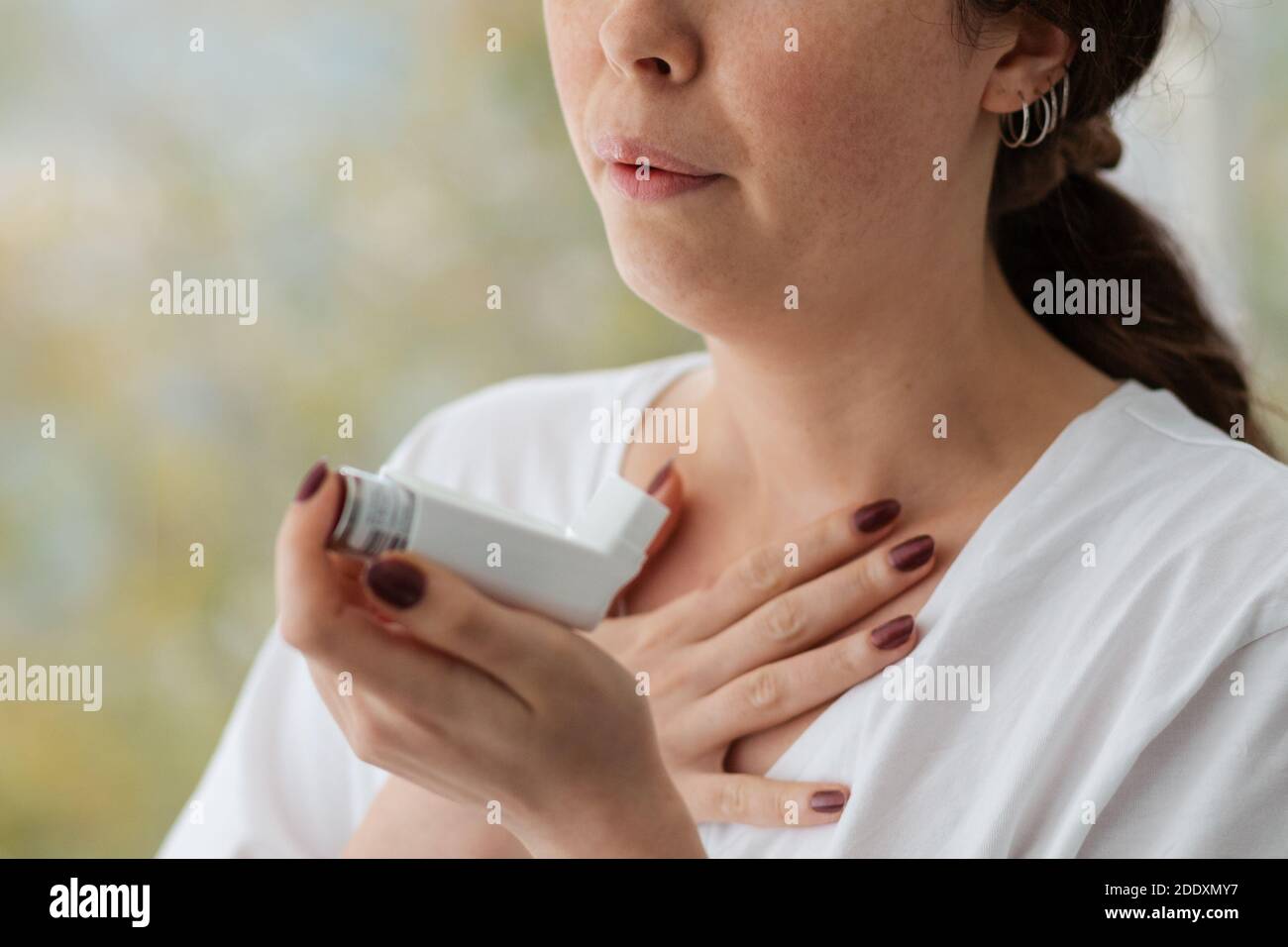 Allergic Asthma. A woman experiencing an asthmatic attack, holding an ...