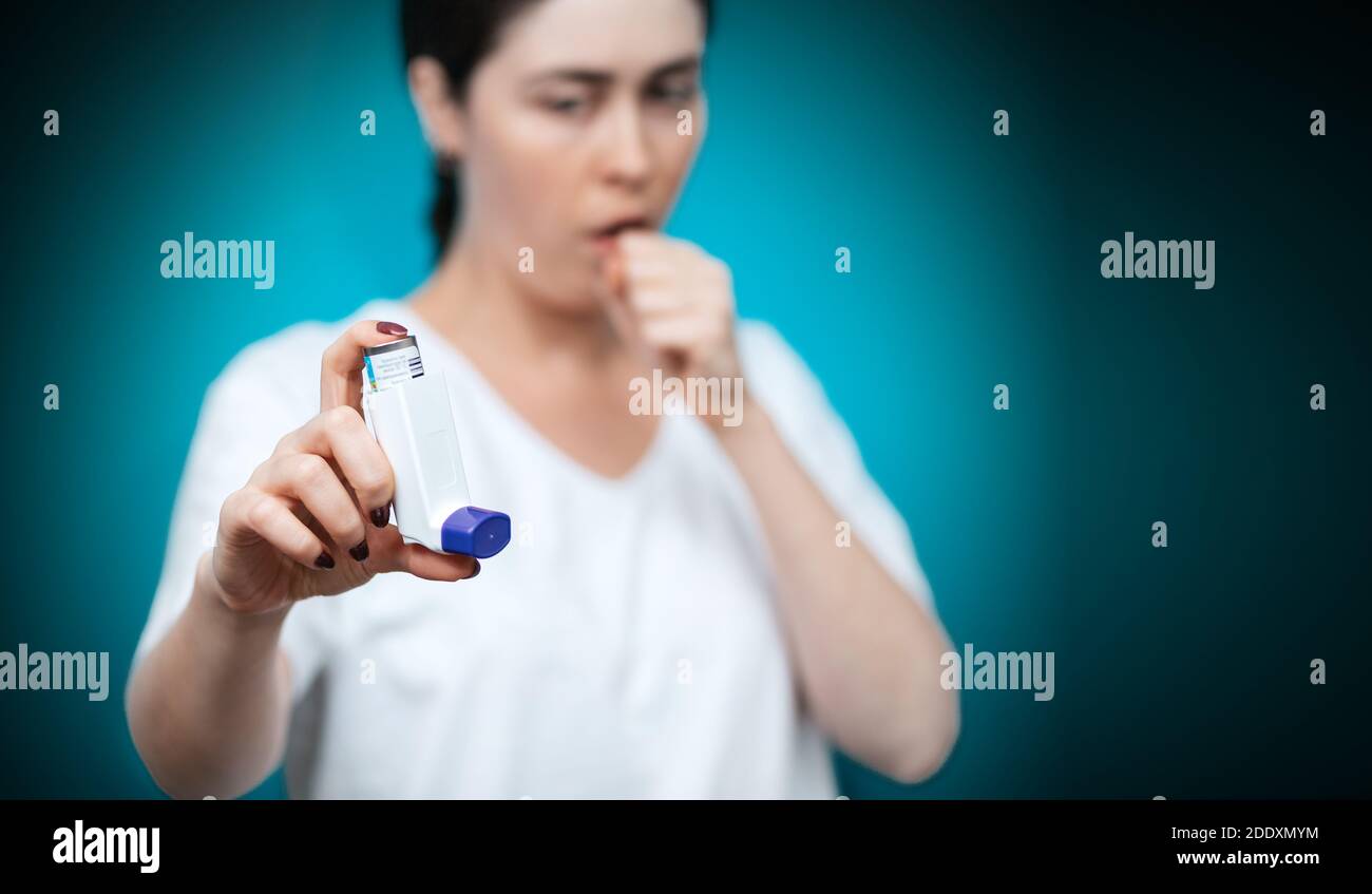 Symptoms of asthma. Portrait of a young coughing woman showing an ...